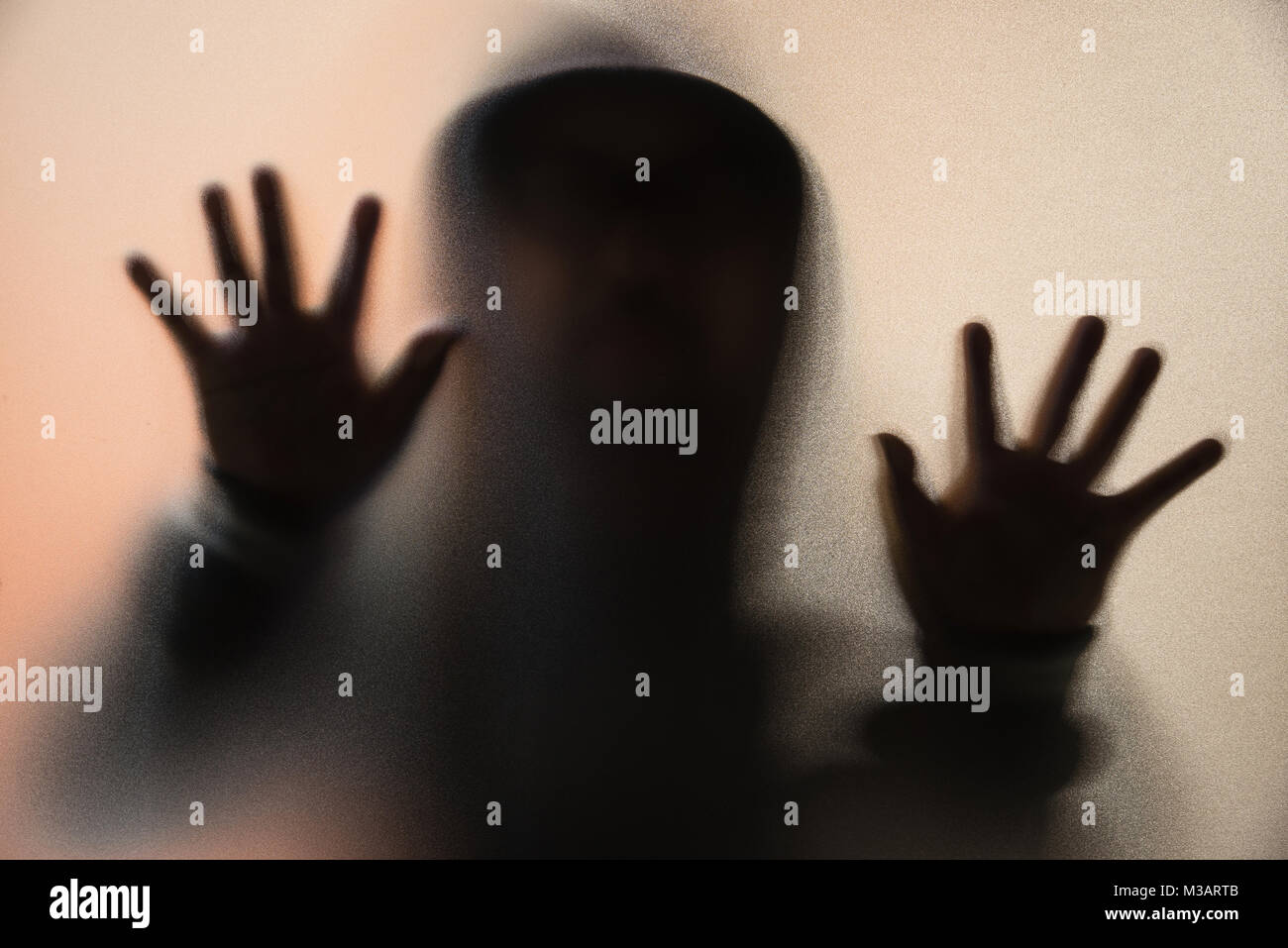 Shadow blur of horror man in jacket with hood.Hands on the glass ...