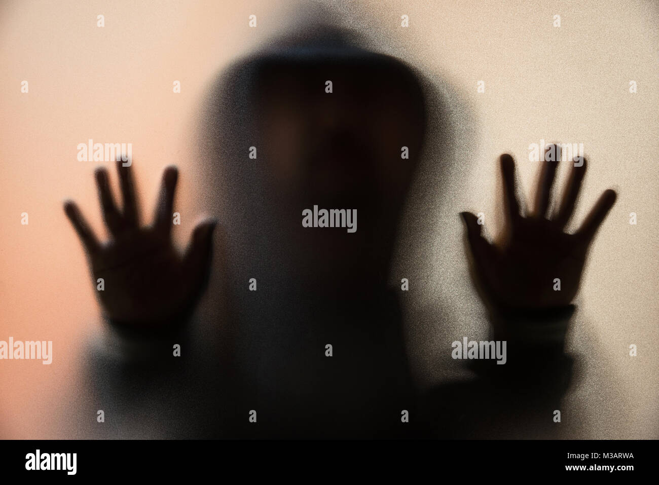 Shadow blur of horror man in jacket with hood.Hands on the glass ...