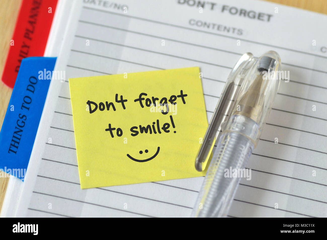 Text don't forget to smile written on a sticky note over an agenda ...