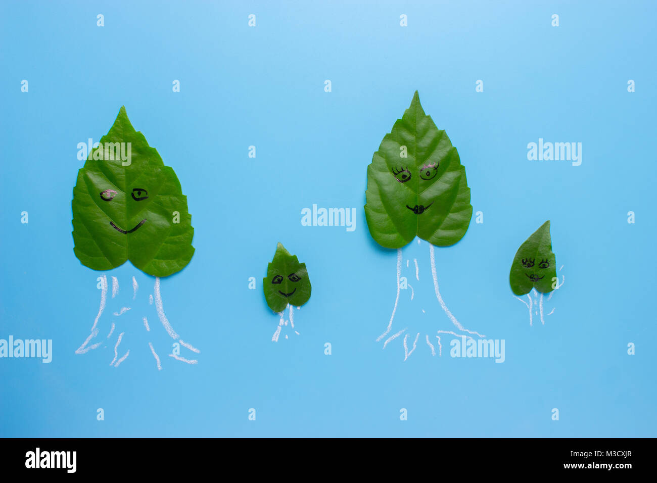 Green cut out paper tree on blue background Stock Photo - Alamy