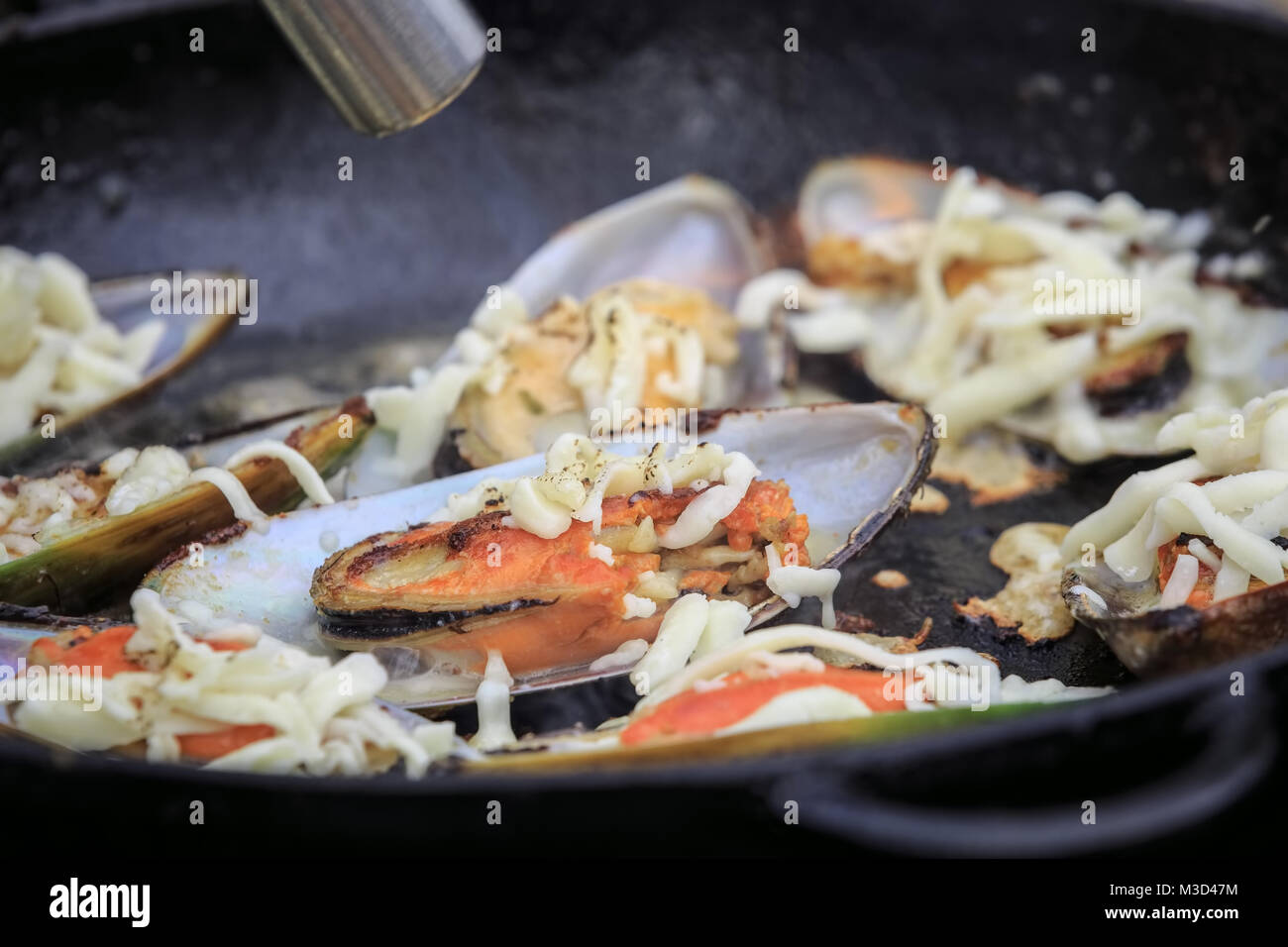 The process of cooking fried mussels with cheese in a frying pan Stock ...