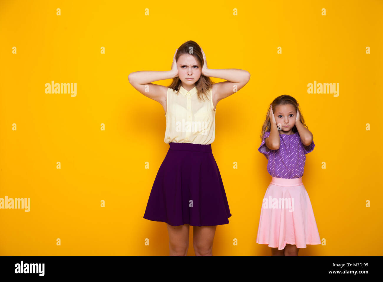 two girls close their ears to hear Stock Photo - Alamy