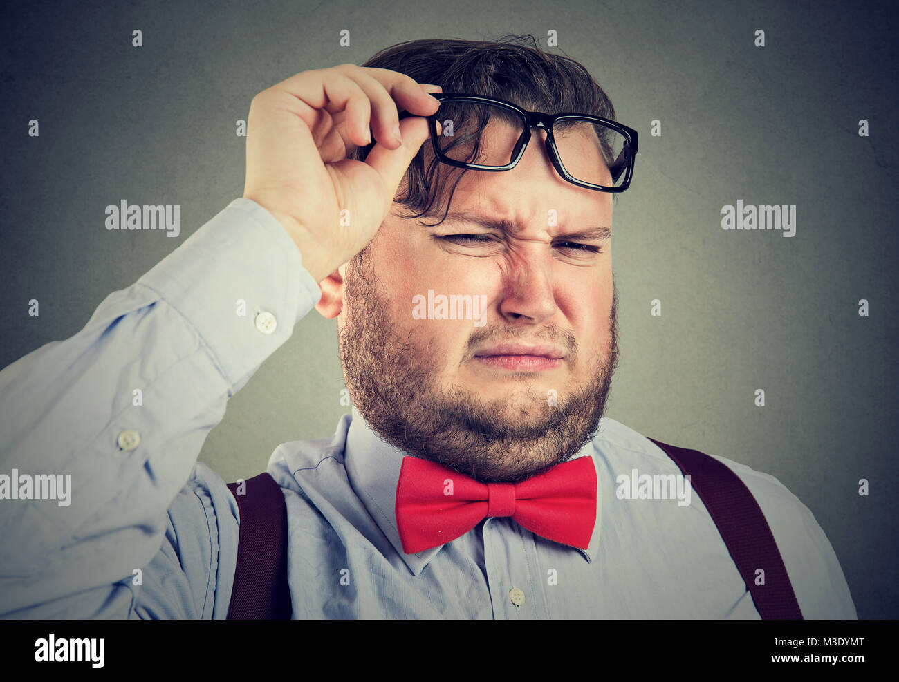 Man wearing eyeglasses and having expression of aversion looking at ...