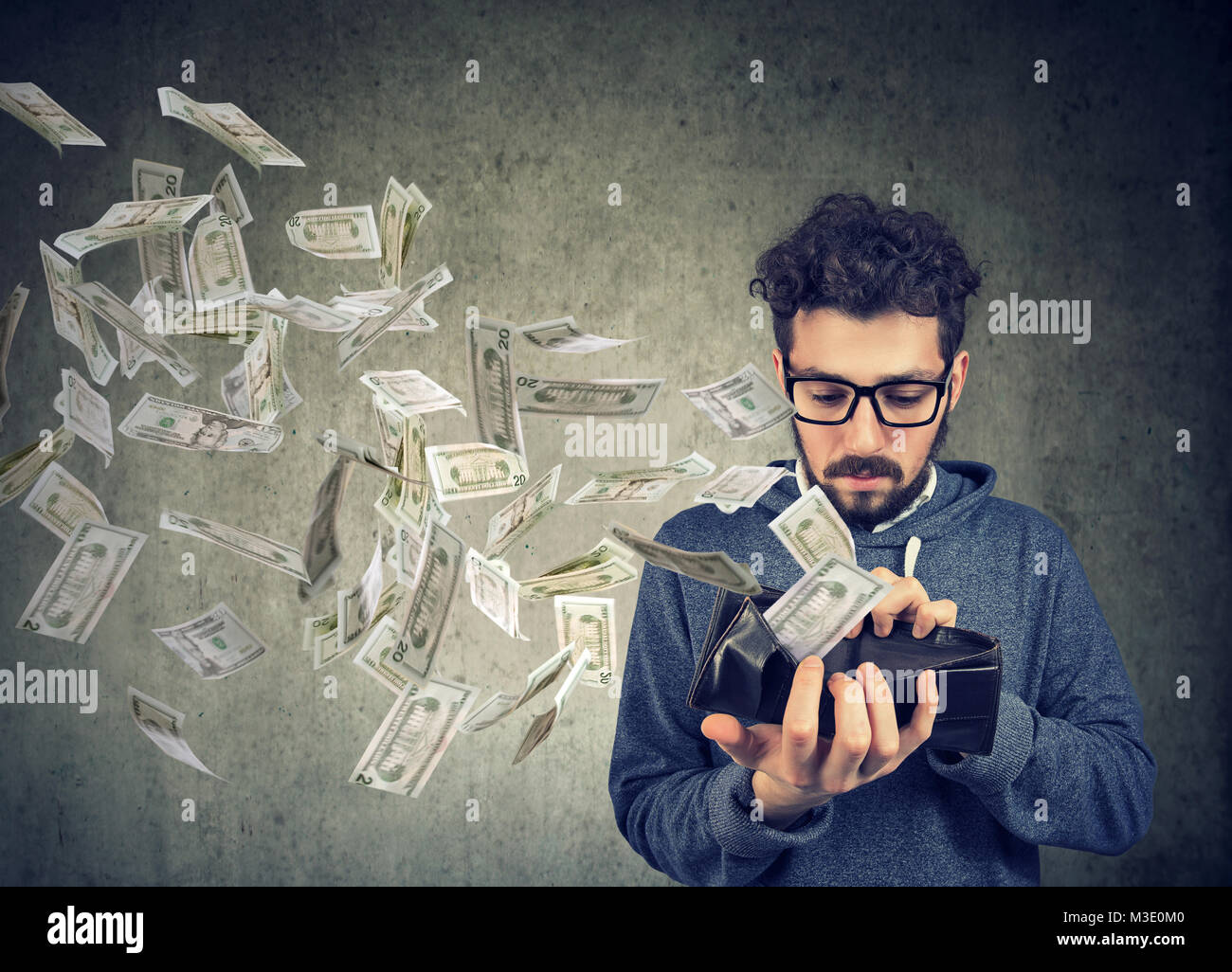 Sad man looking at his wallet with money dollar banknotes flying out ...