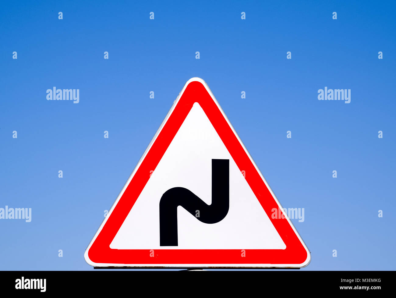 Road sign dangerous turn. Warning sign Stock Photo - Alamy