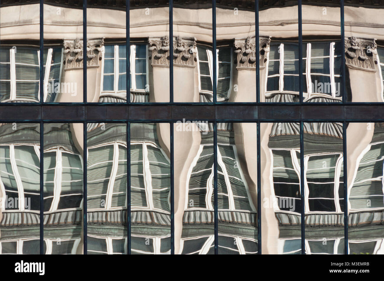warped reflection of old building in windows of new glass front modern ...