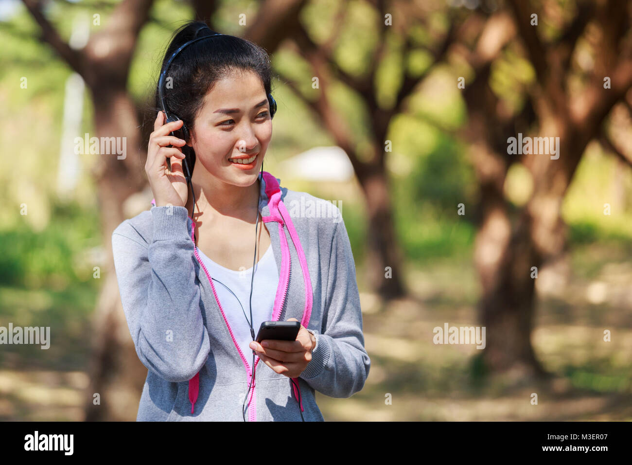 young sporty woman using smartphone with headphone in the park Stock ...