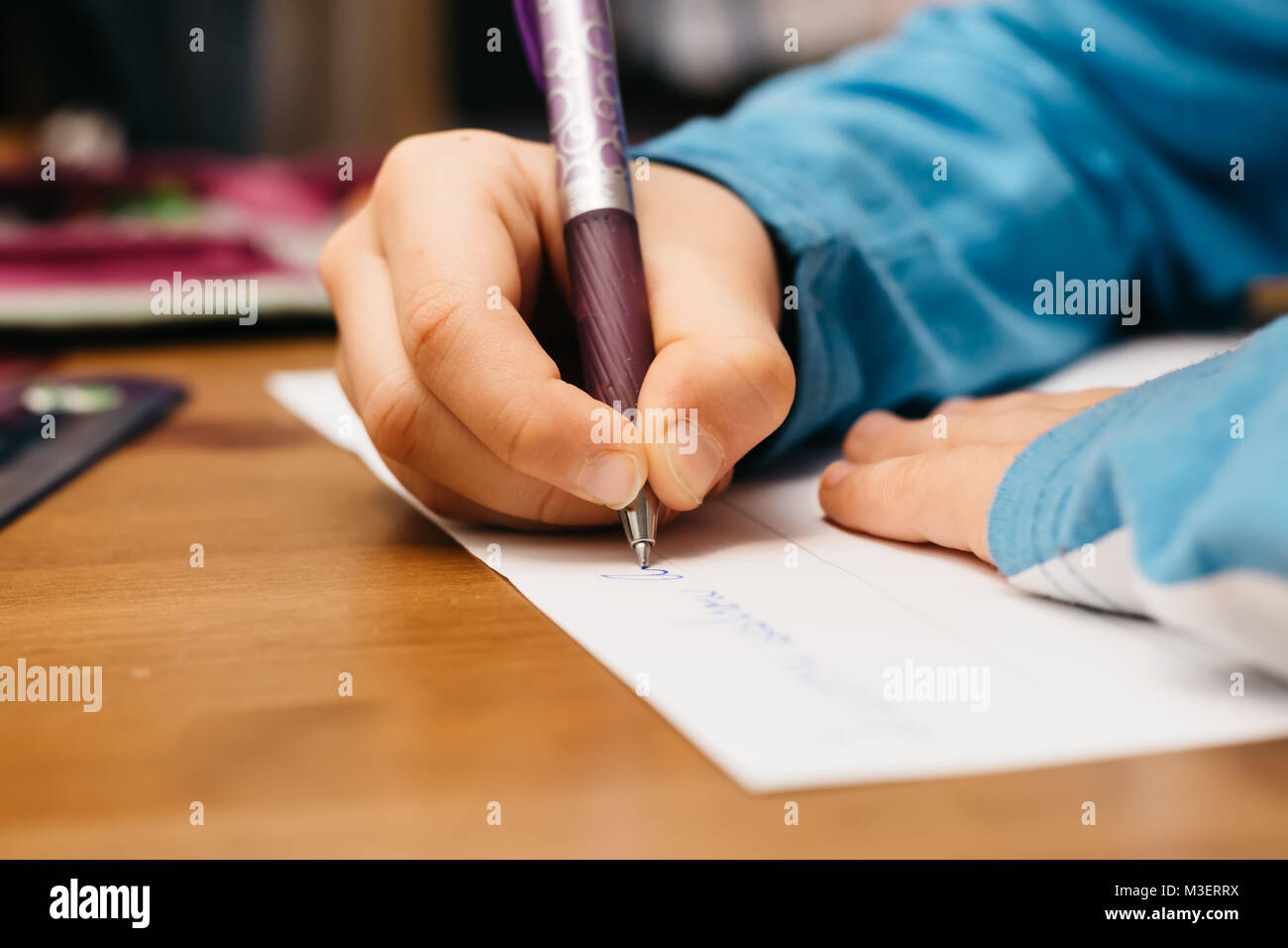 Child doing homework. A young girl writes on paper and uses a pen Stock ...