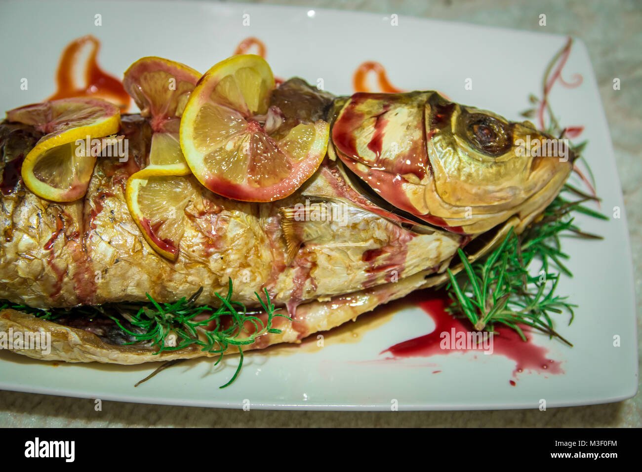Fish with lemon wedges and a green rosemary. Shallow depth of field ...