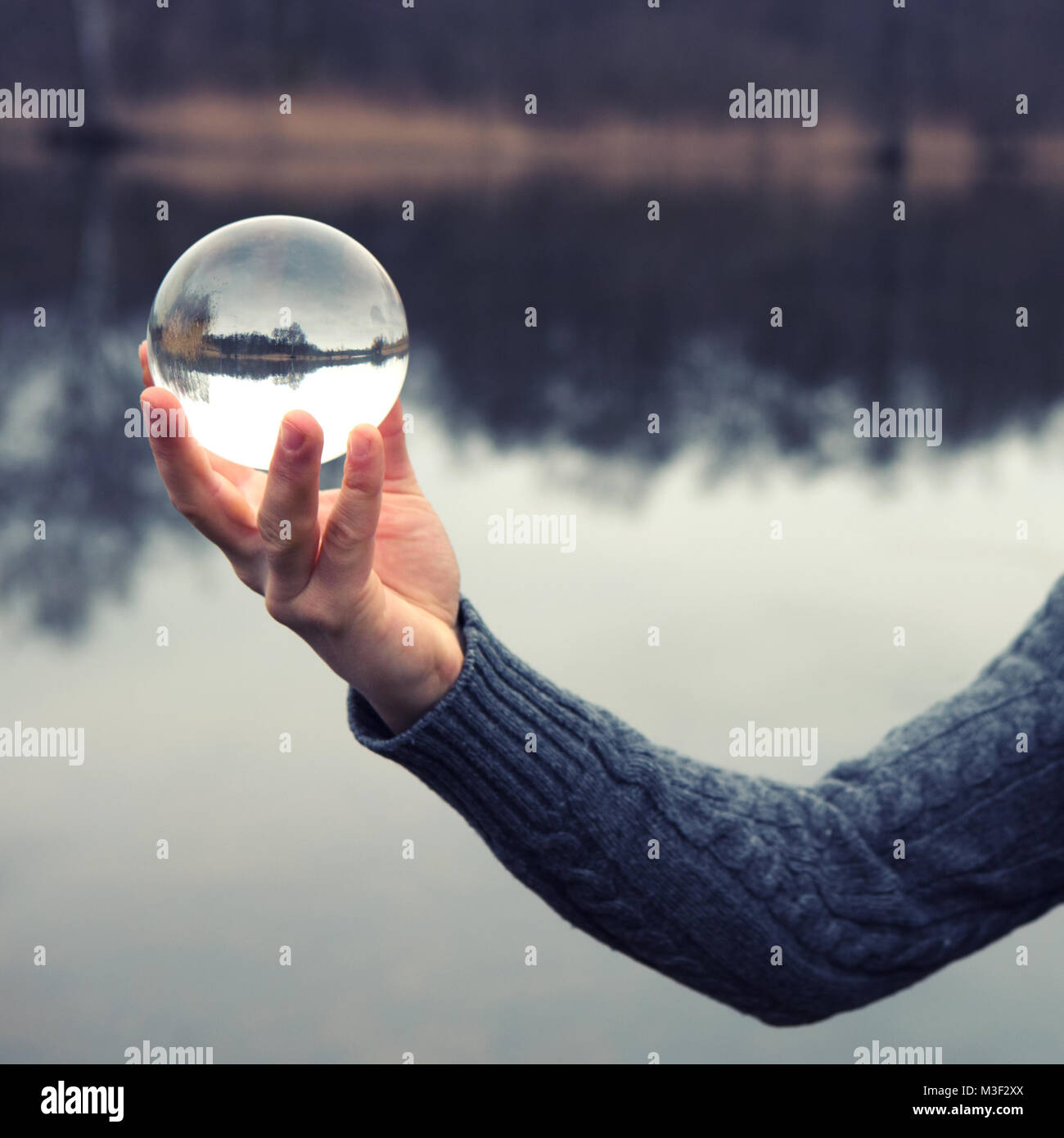 closeup of hand holding a glass ball in front of lake Stock Photo - Alamy
