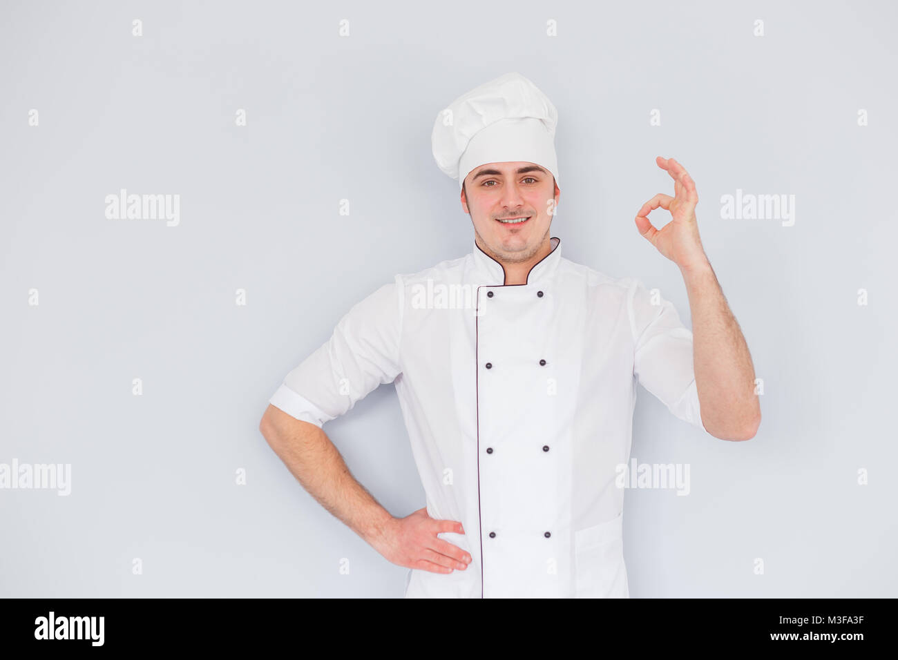 Young chef cook shows ok on a white background Stock Photo - Alamy