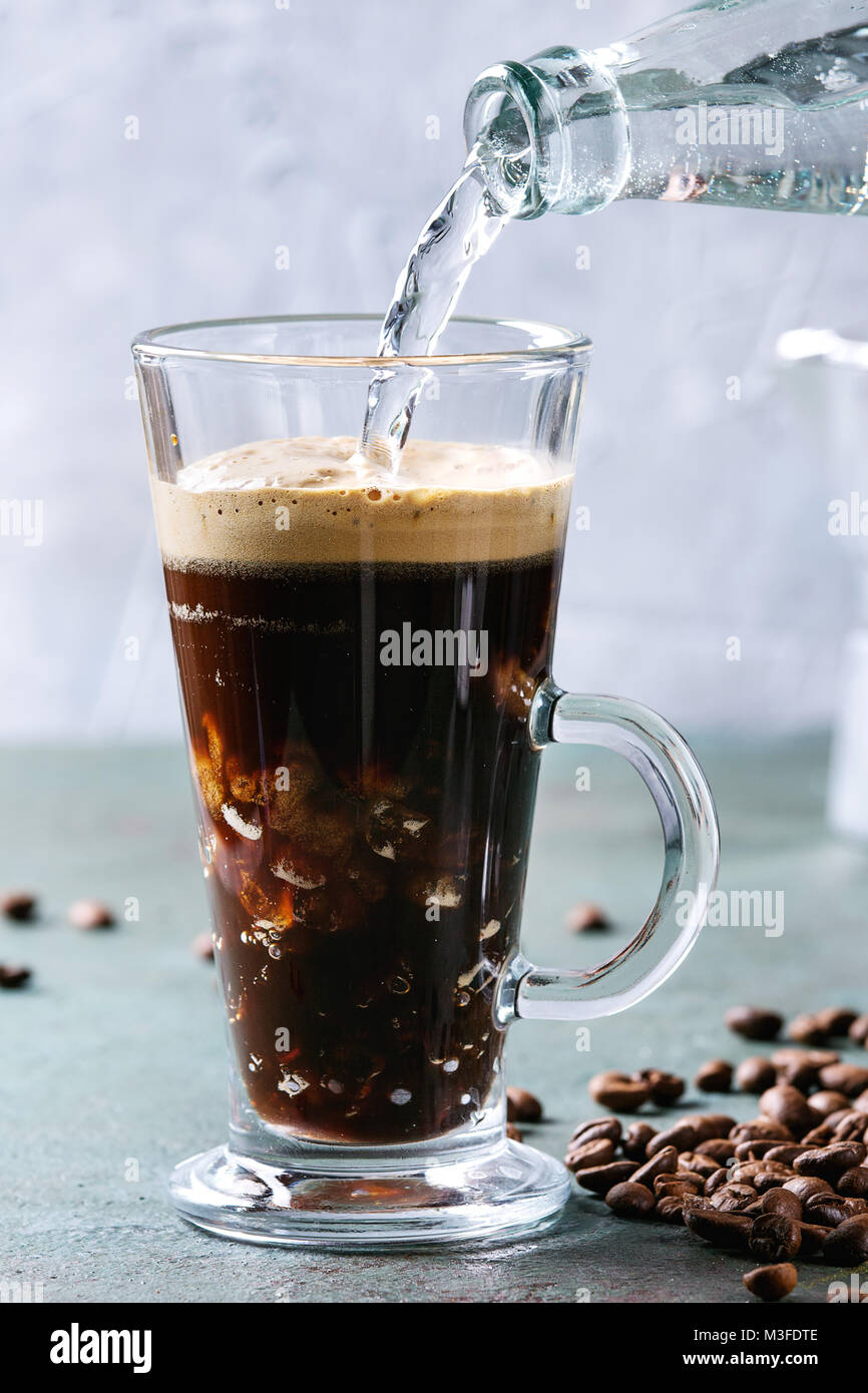 Fizzy iced Coffee espresso with pouring sparkling water from bottle and ...