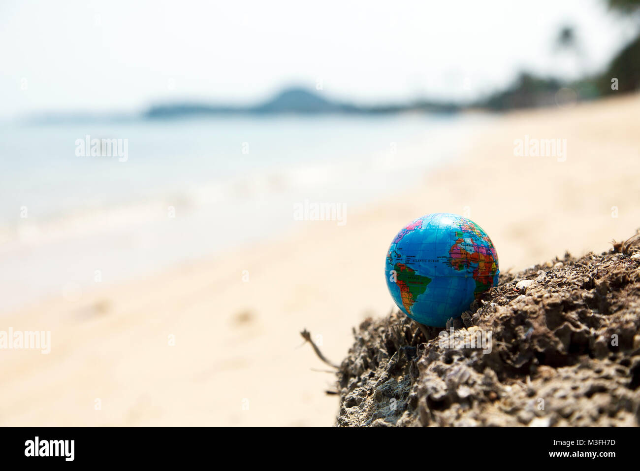 small earth globe lies on a rock on a tropical beach Stock Photo - Alamy