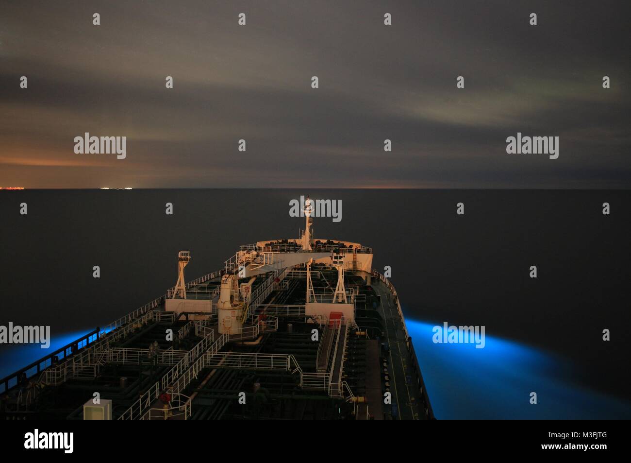 A long exposure photo taken from the bridge of ship at night. The blue ...