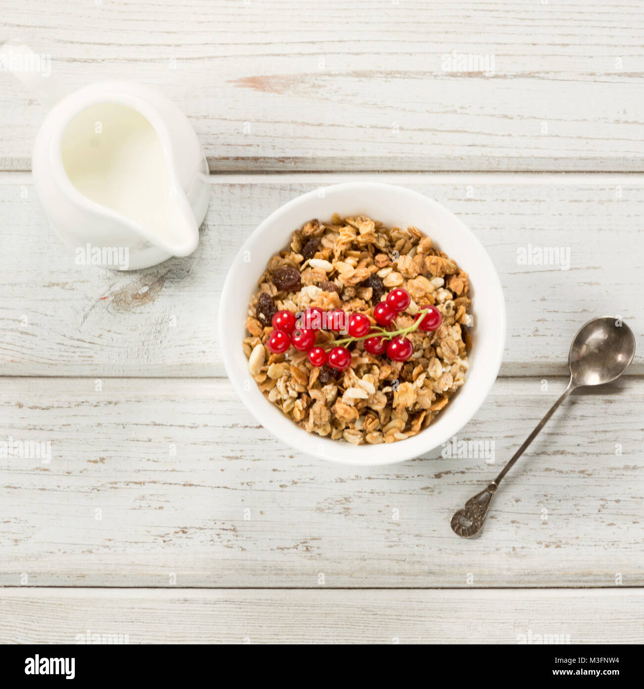 Summer healthy breakfast of granola, muesli with milk jug with red ...