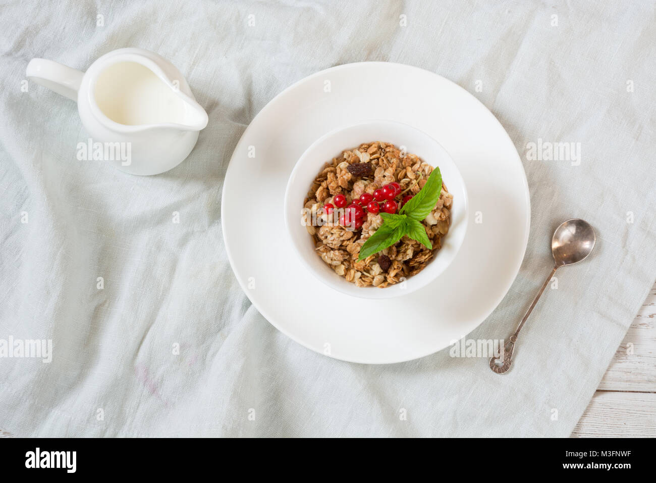 Summer healthy breakfast of granola, muesli with milk jug with red ...