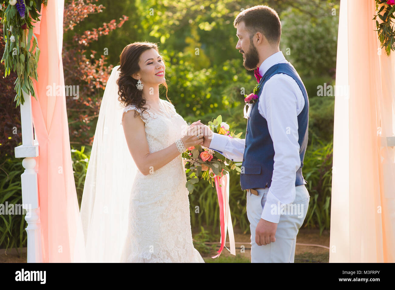 Bride and groom holding each other under the arch at the garden Stock ...