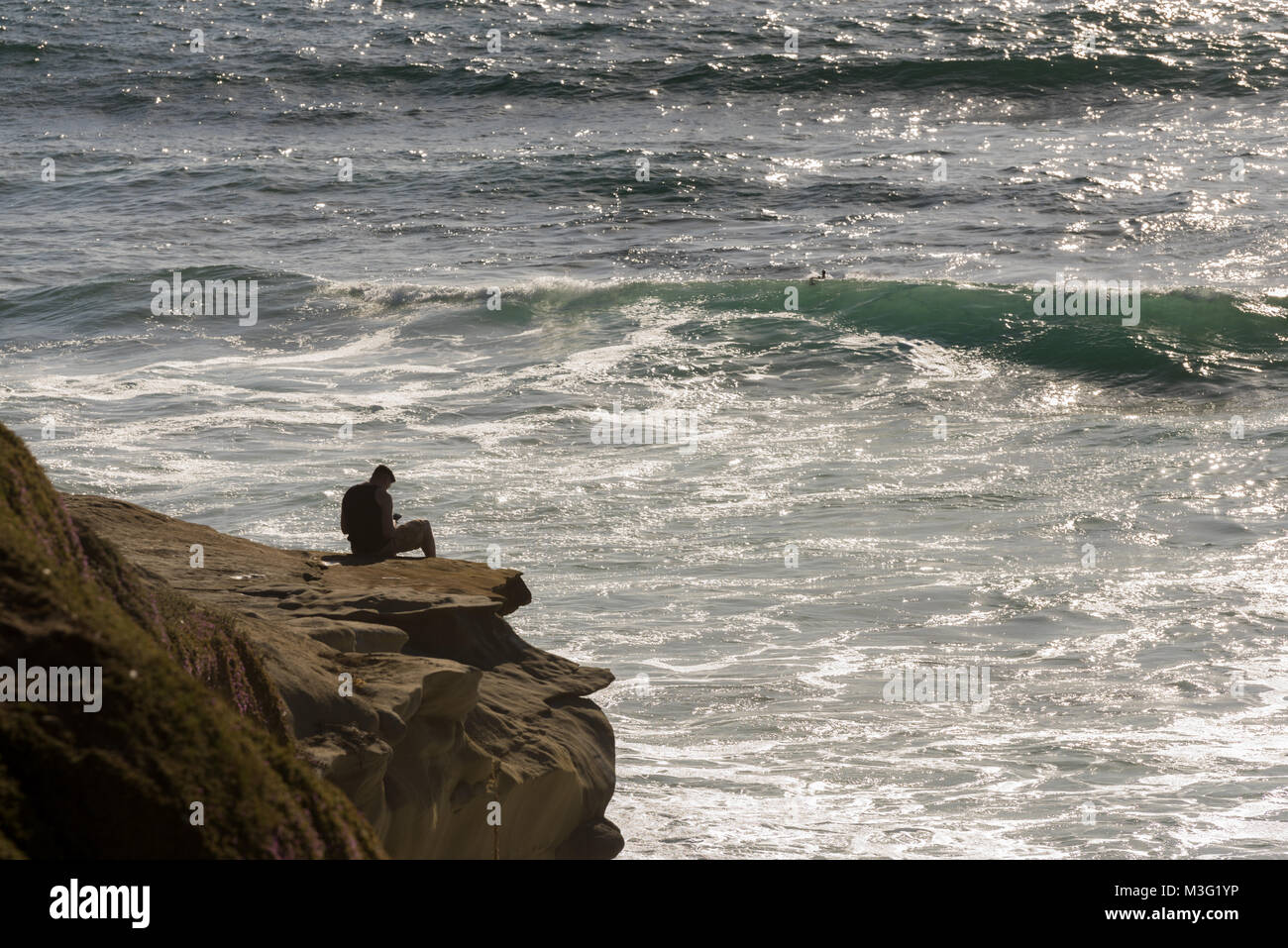 Man sitting on cliff overlooking the Pacific Ocean Stock Photo - Alamy