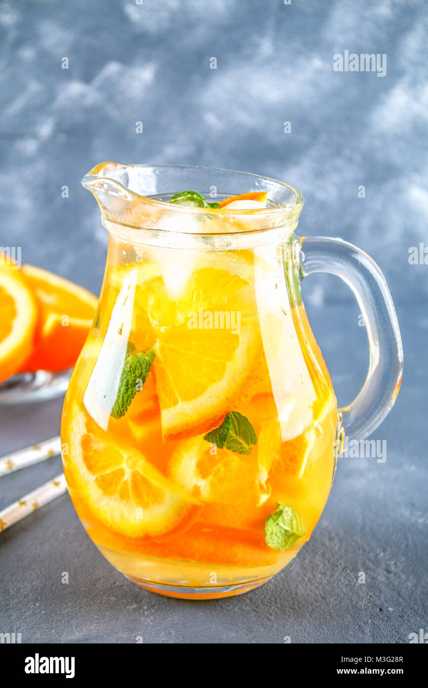 Orange detox water in a pitcher on a gray concrete background. Healthy ...