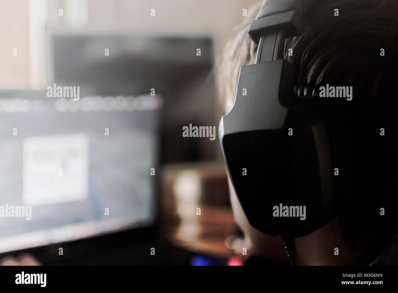 Teen boy with headphones, back of head at computer Stock Photo - Alamy