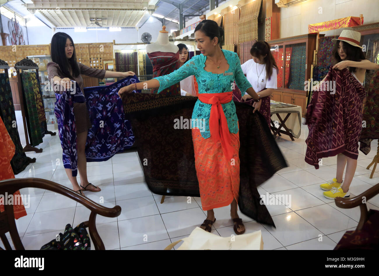 A local guide showing tourist the correct way to wear Sarong.Tenun Ikat ...