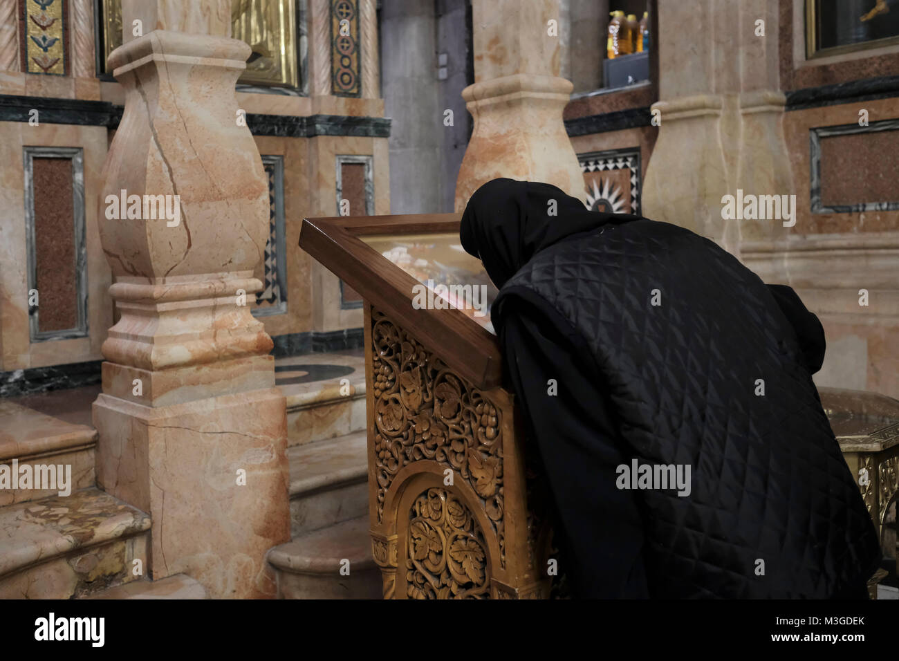 Eastern Orthodox nun kissing a religious icon inside the Katholikon or ...