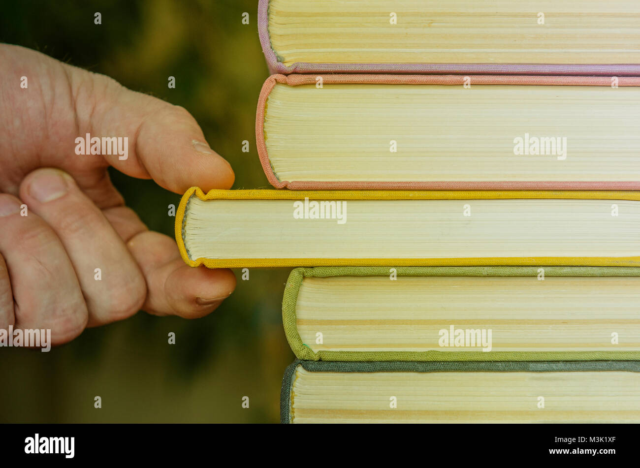 a man's hand pulls a book out of the shelfю close-up. education concept ...