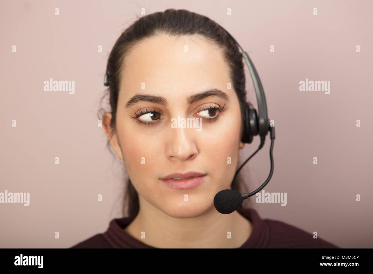 Studio shot close-up portrait of a young woman thinking while listening ...