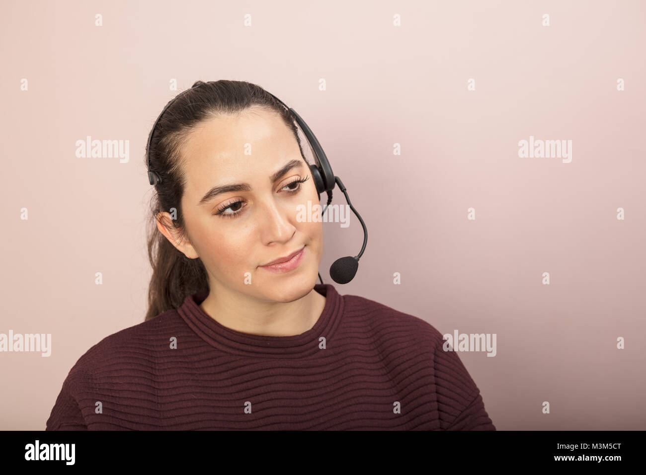 Dark-haired woman sitting with headset in call center in a concept of ...