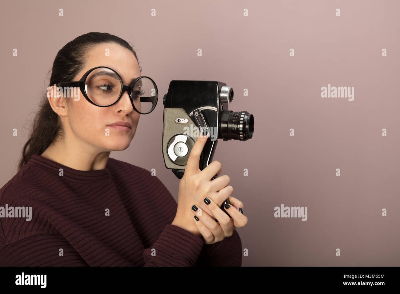 Attractive woman photographer wearing nerdy glasses peering into the ...