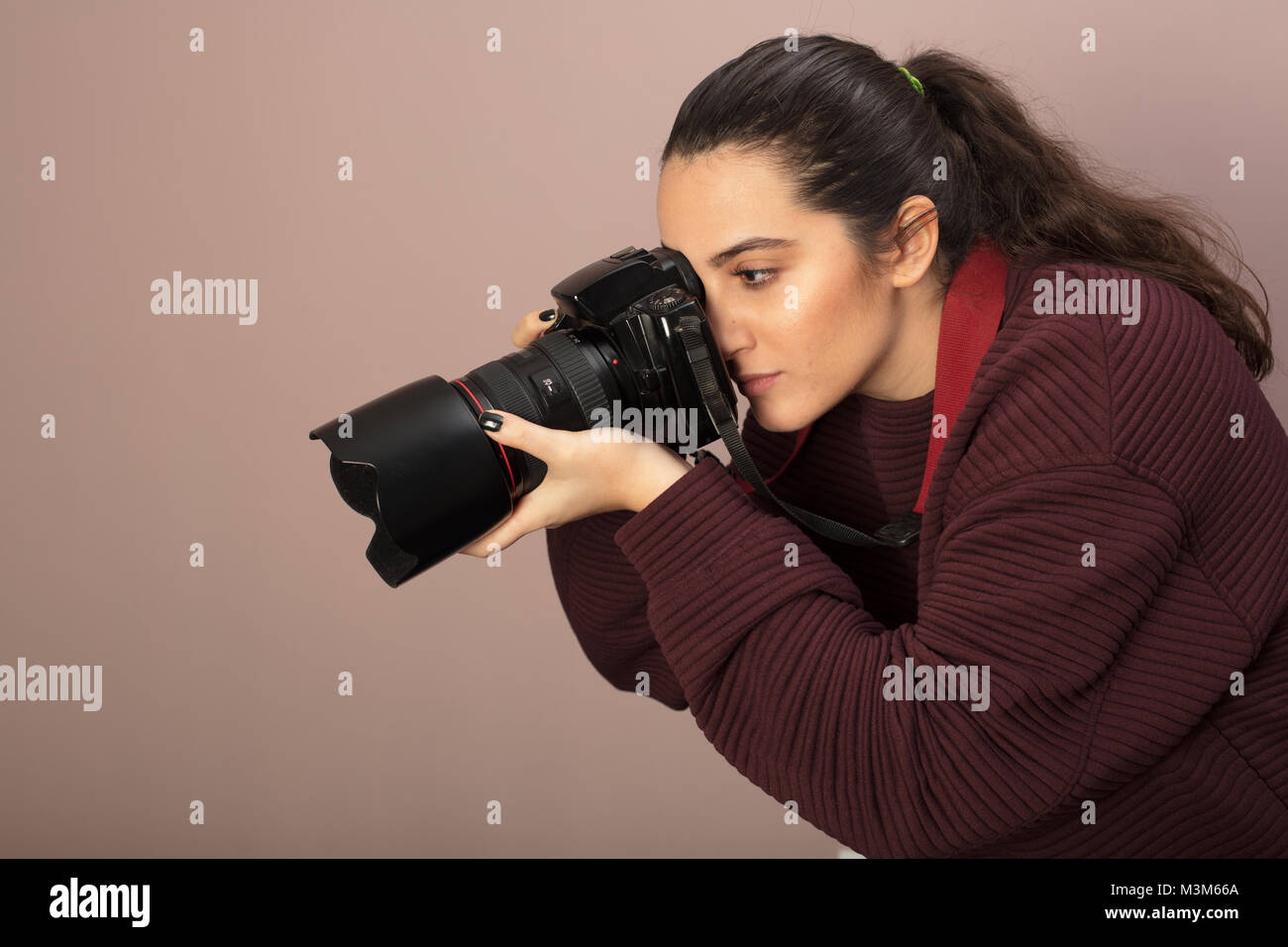 Young woman photographer taking a photo with a professional DSLR and ...