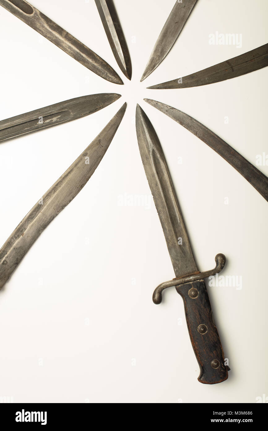 Isolated old dagger with assorted blades of weapons all pointing to a ...