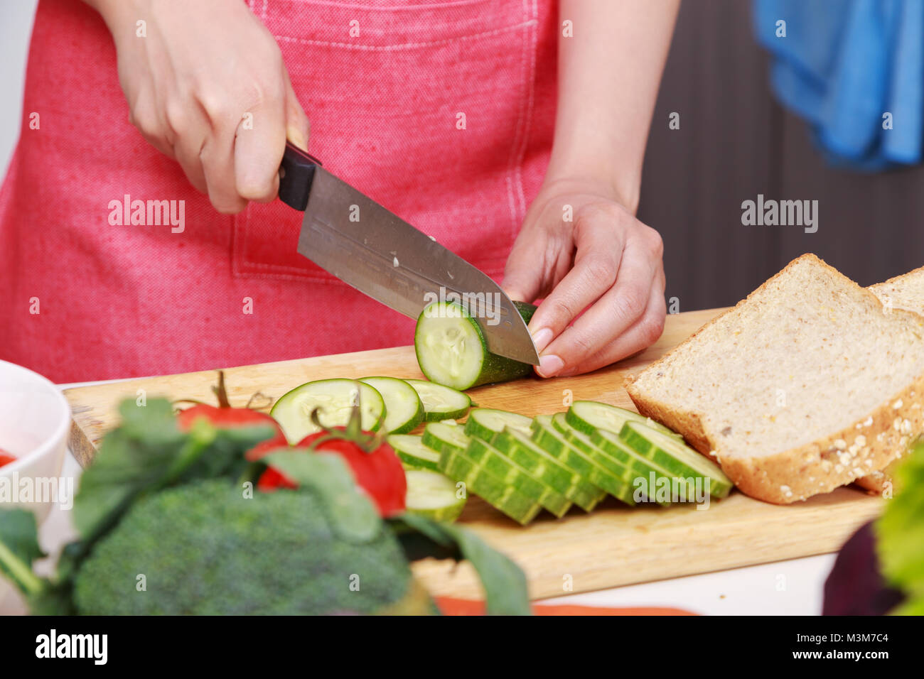 close up of hand cutting cucumber on board in kitchen room Stock Photo ...