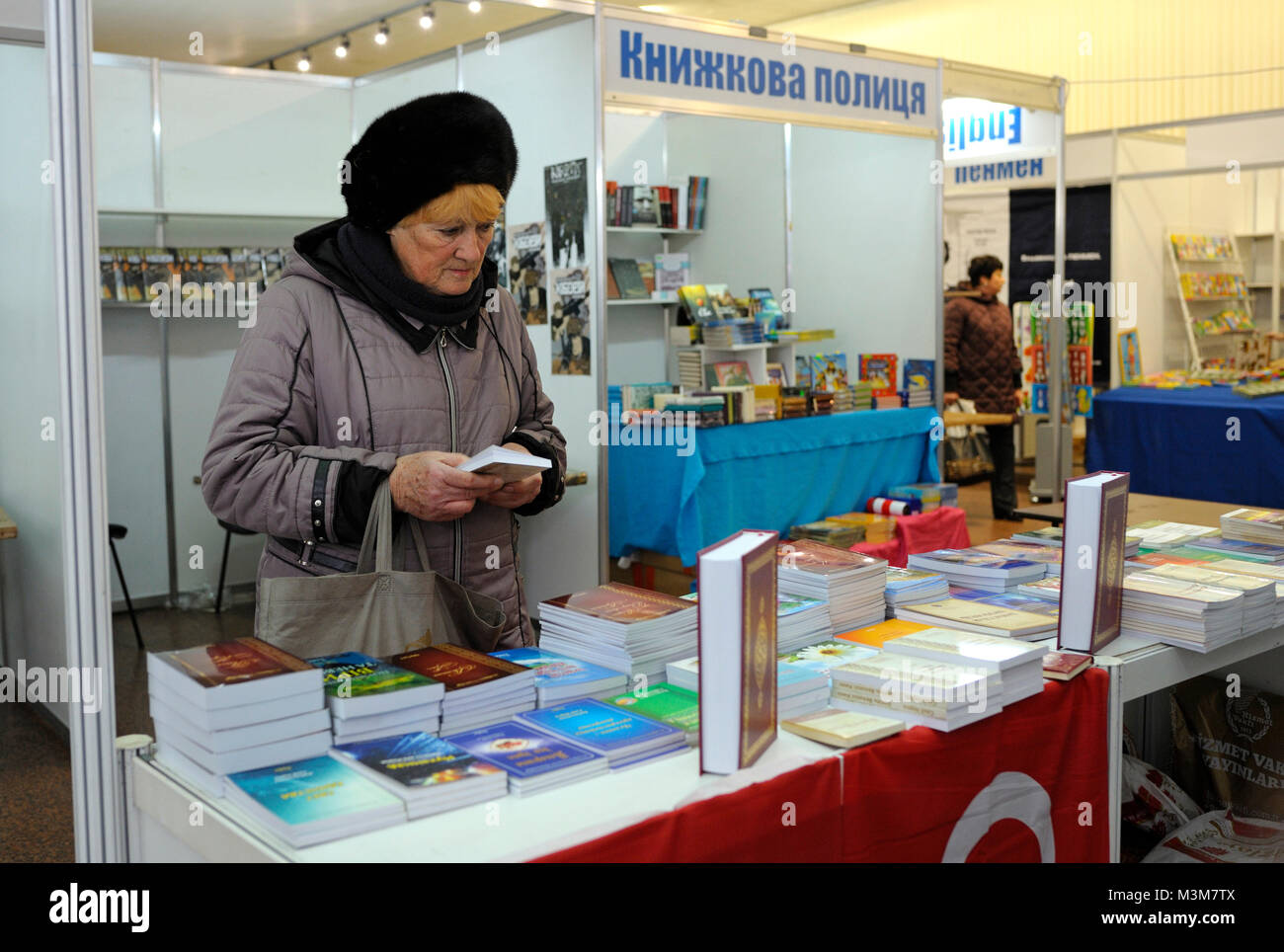 Customers standing in front of a bookshop counter and reading new ...