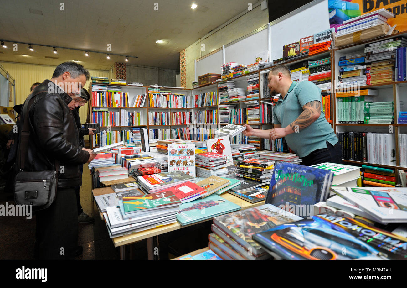 Customers standing in front of a bookshop counter and reading new ...