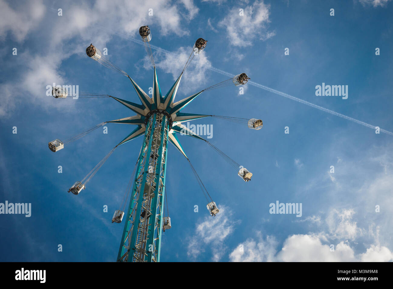 White and blue high chair swing ride in fun fair with a blue sky with ...
