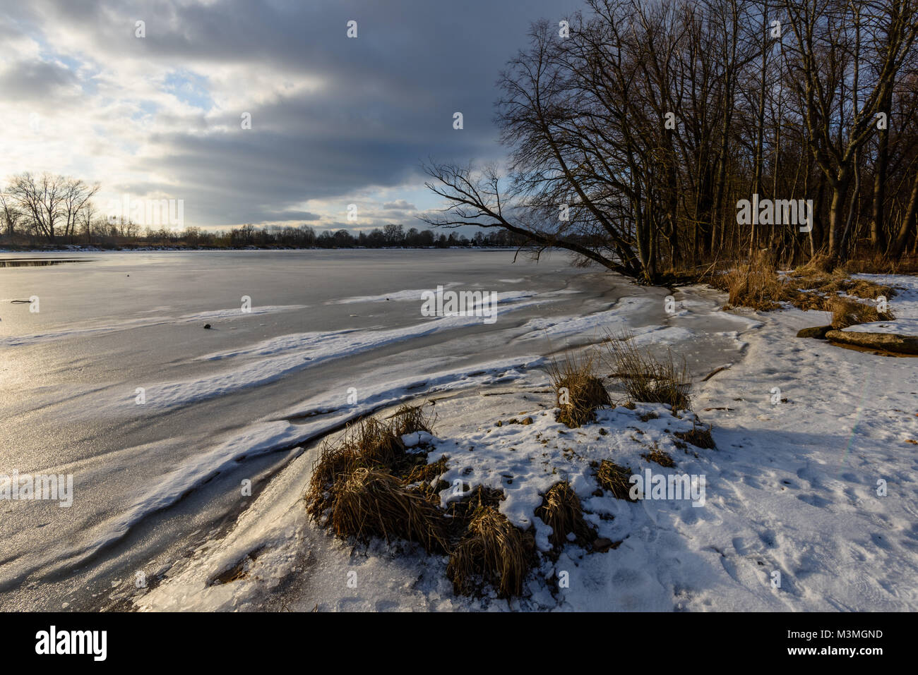 colorful winter sunset on frozen river ice with dramatic clouds and ice ...