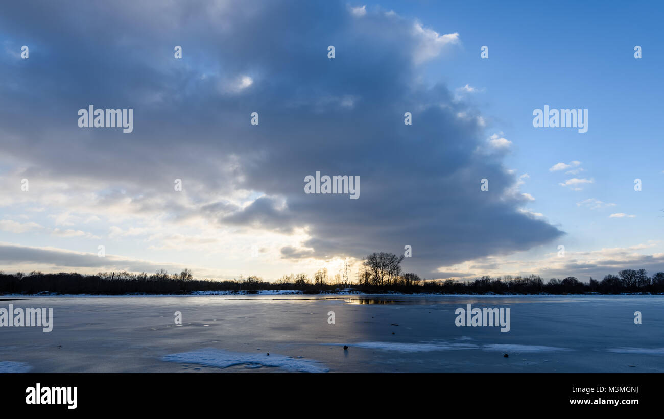 colorful winter sunset on frozen river ice with dramatic clouds and ice ...