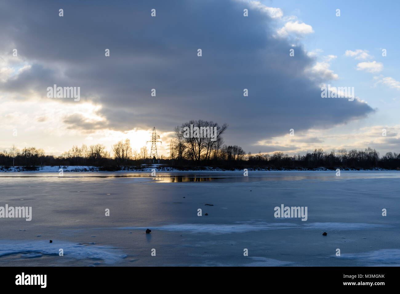 colorful winter sunset on frozen river ice with dramatic clouds and ice ...