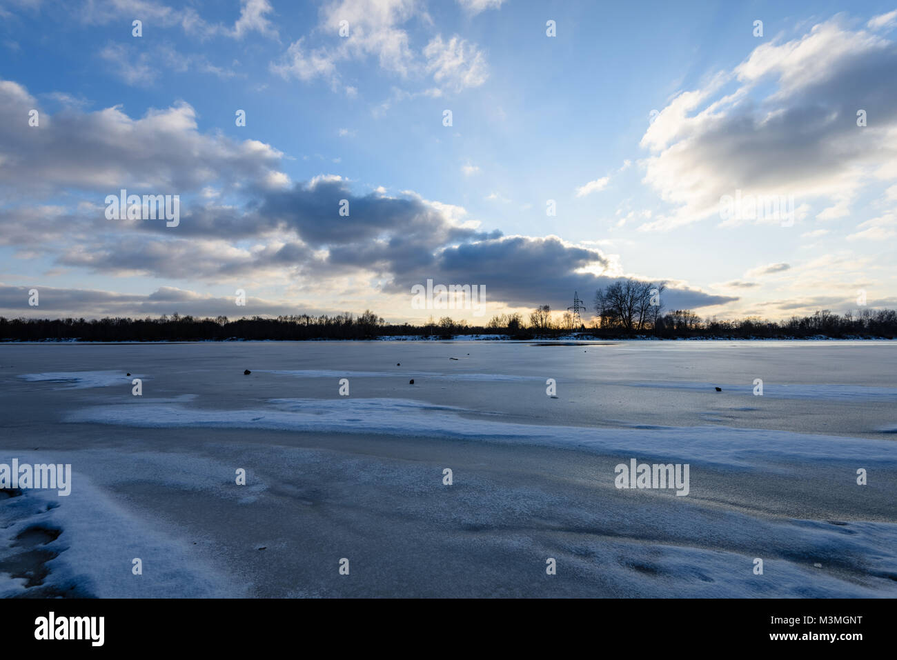 colorful winter sunset on frozen river ice with dramatic clouds and ice ...