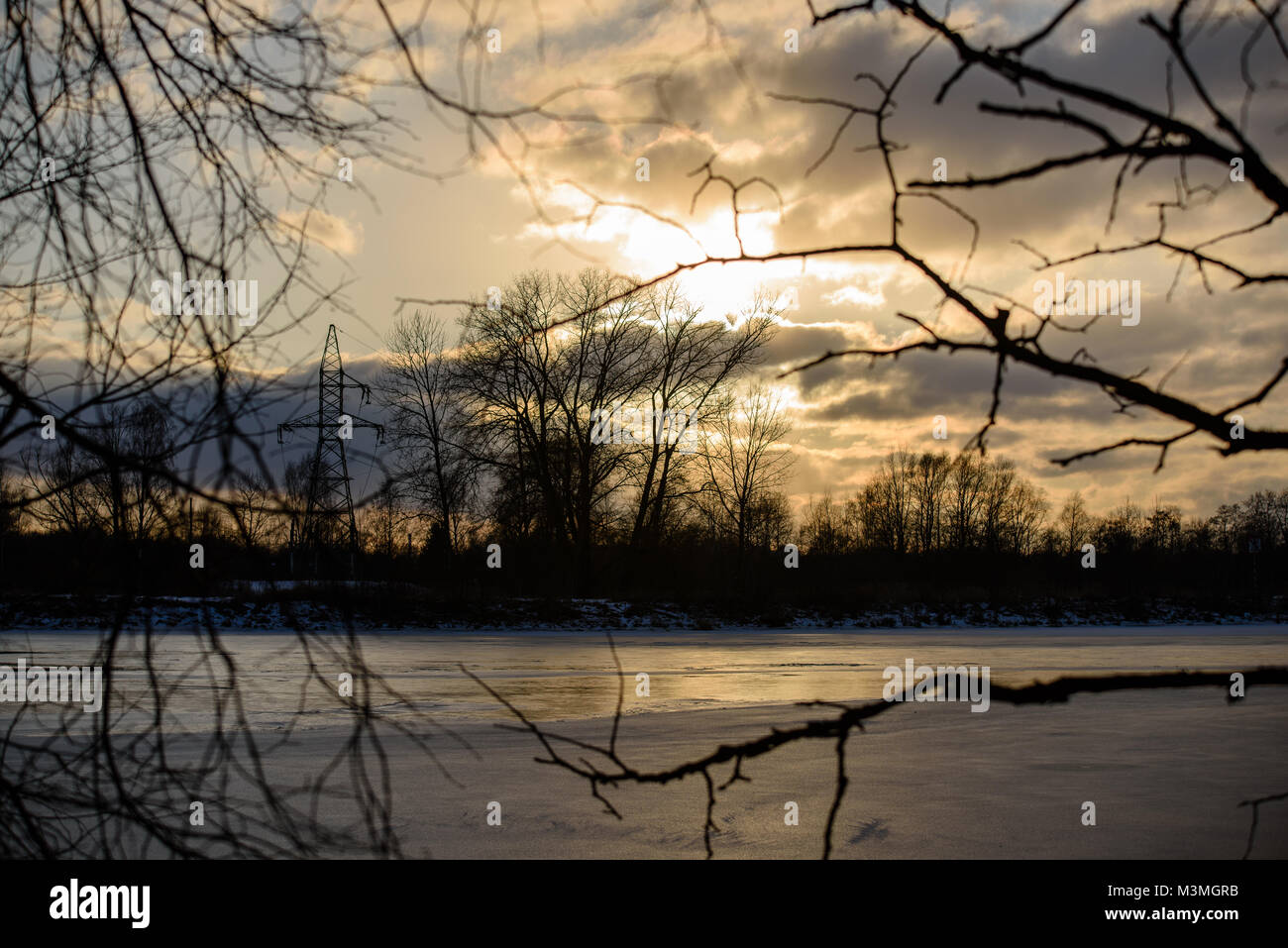 colorful winter sunset on frozen river ice with tree silhouettes and ...