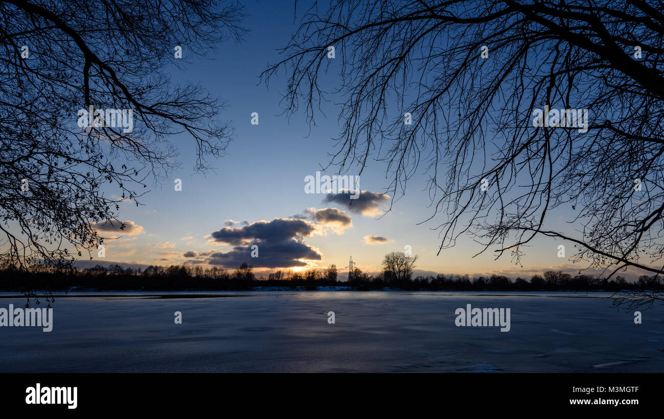 colorful winter sunset with light rays coming through the trees on the ...