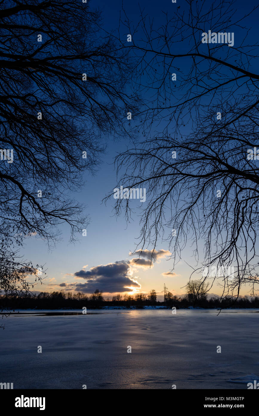 colorful winter sunset with light rays coming through the trees on the ...