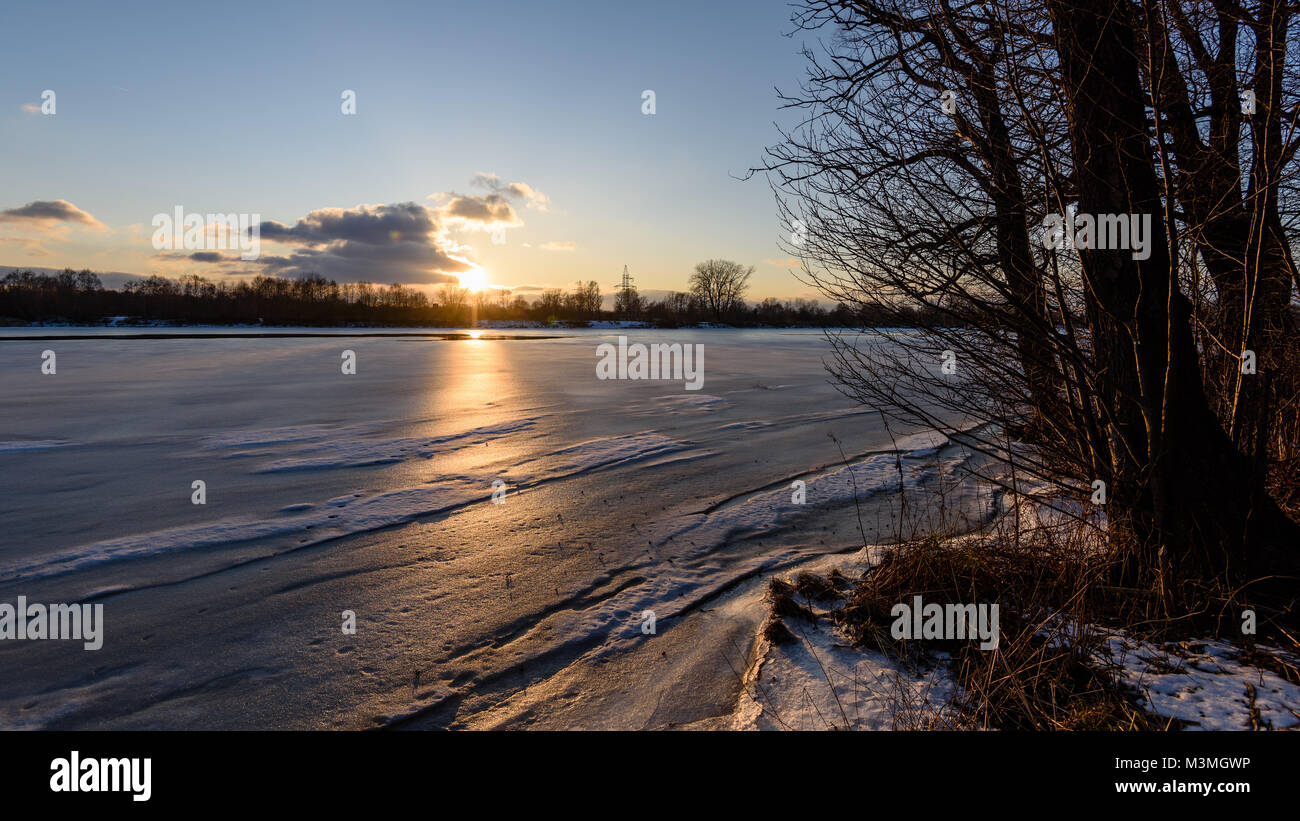 colorful winter sunset with light rays coming through the trees on the ...
