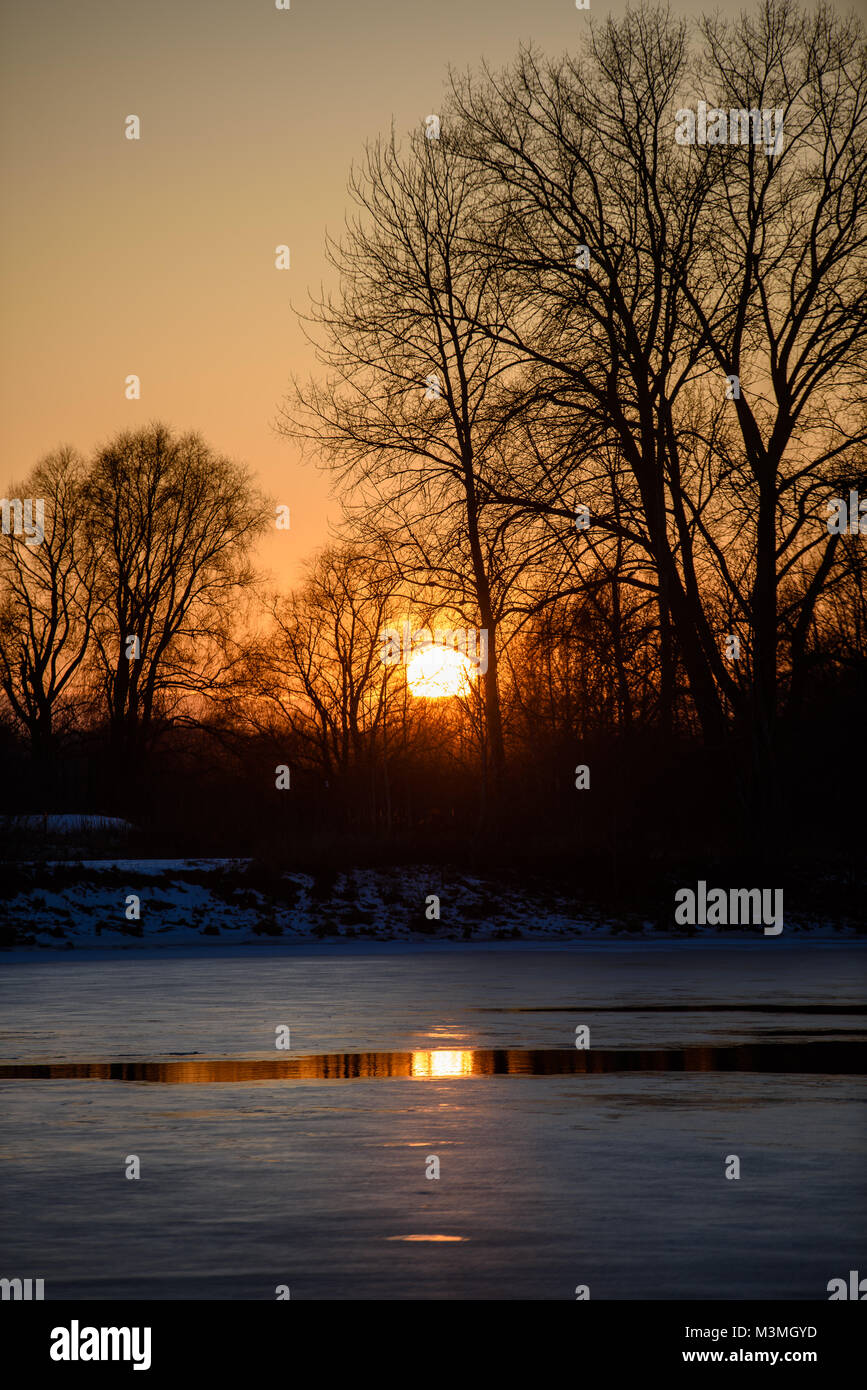 colorful winter sunset with trees and power lines in background and ice ...