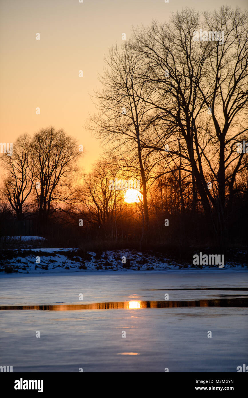 colorful winter sunset with trees and power lines in background and ice ...