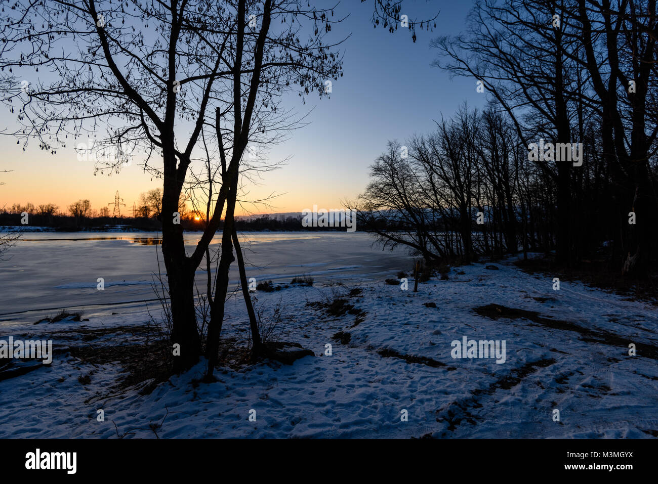 colorful winter sunset with light rays coming through the trees on the ...