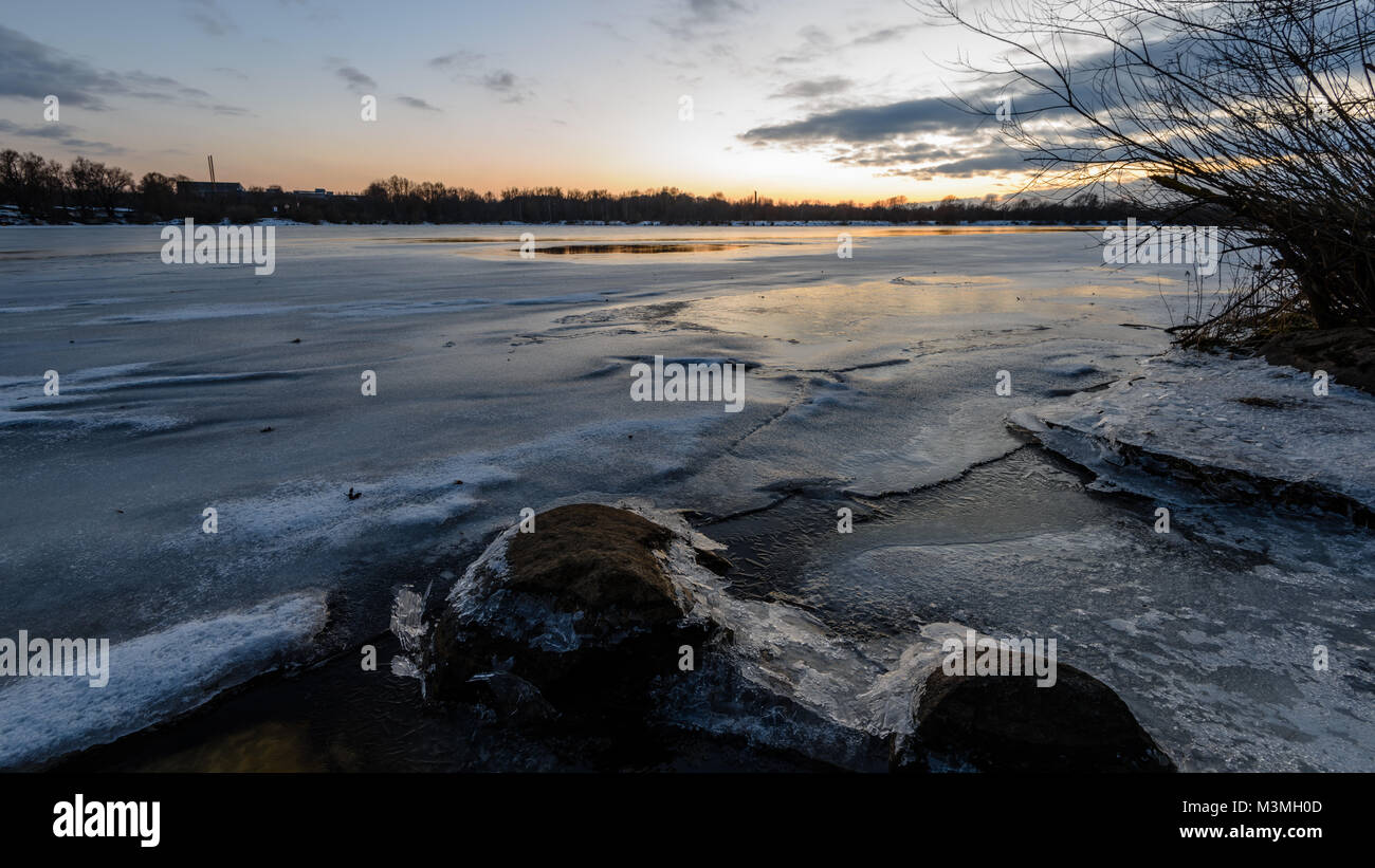colorful winter sunset on frozen river ice with dramatic clouds Stock ...