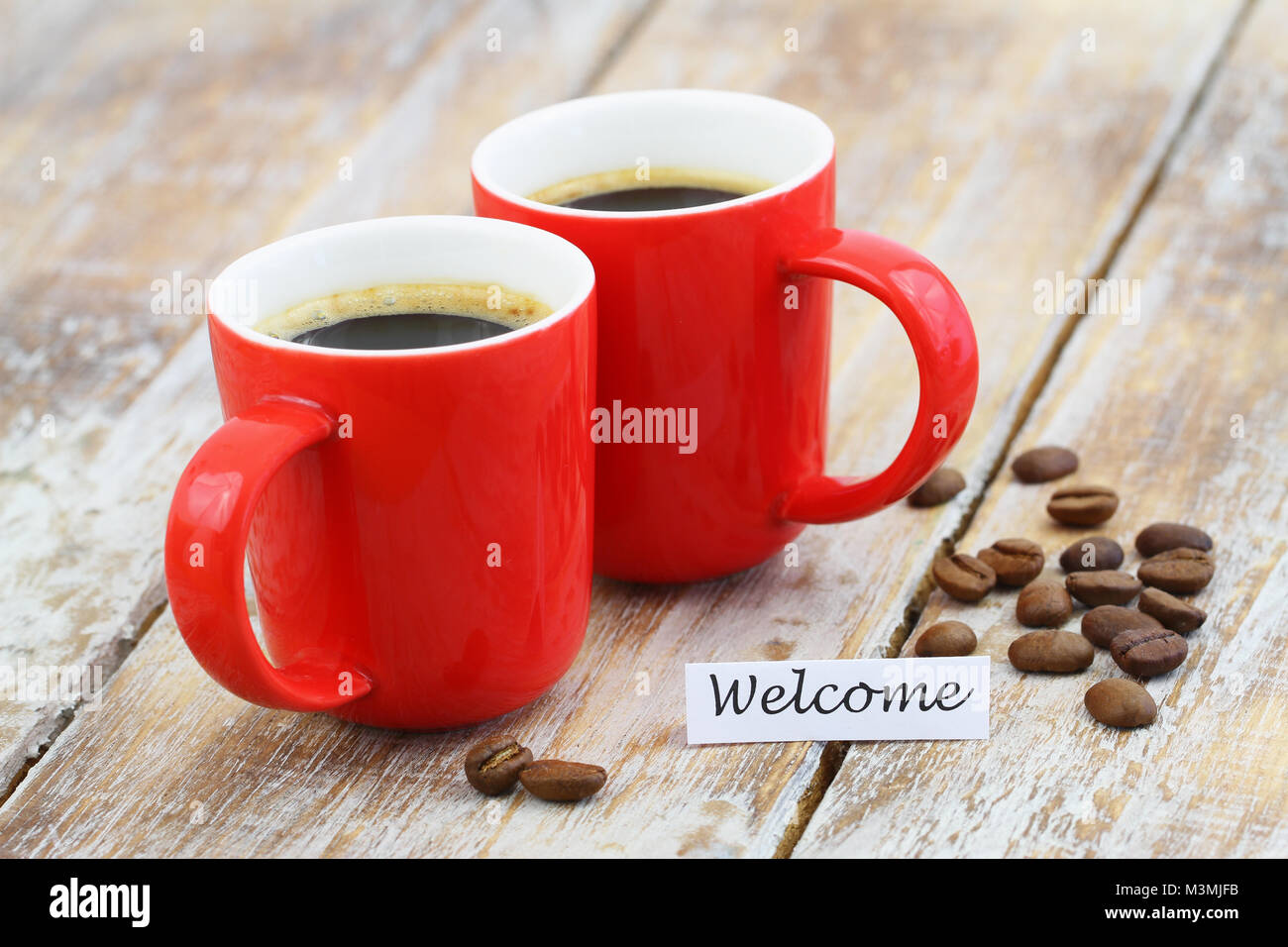 Welcome card with two red mugs with coffee and coffee beans on rustic ...