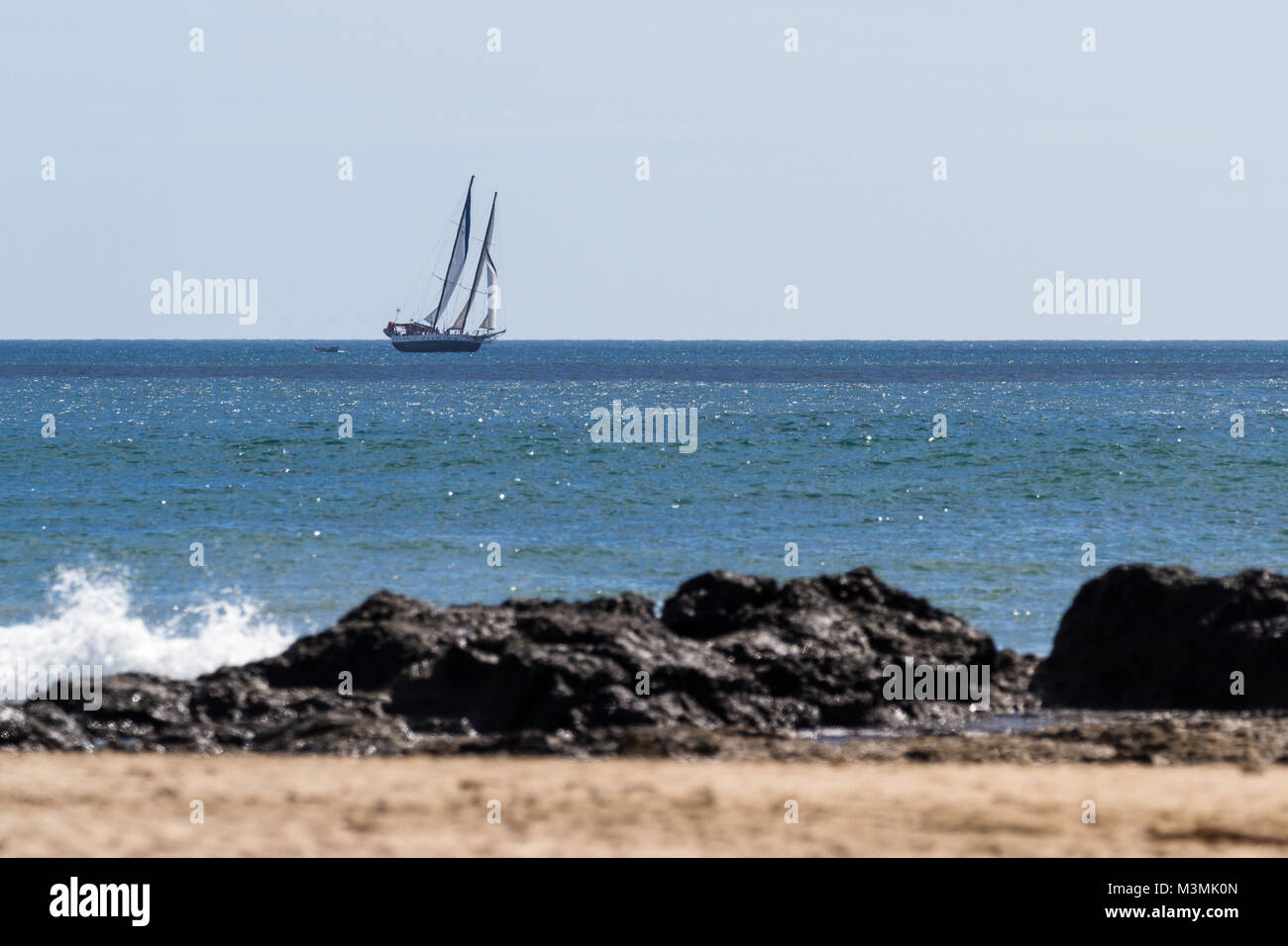 Sail boat crossing the northern pacific beaches of Costa rica on a calm ...